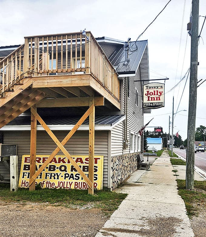 Tovey's Jolly Inn stands proudly along the roadside, its wooden deck and straightforward signage promising authentic Michigan comfort without the frills.