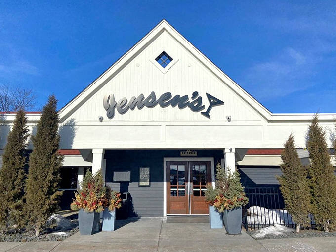Jensen's welcoming exterior stands proudly in Eagan, its white clapboard and signature sign promising culinary delights within. Those evergreens aren't just pretty&mdash;they're your first hint of Minnesota hospitality.