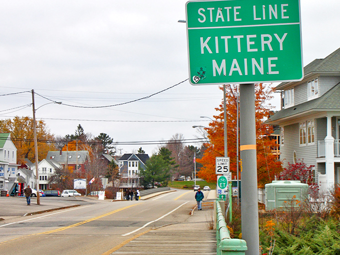 The iconic green "STATE LINE KITTERY MAINE" sign welcomes visitors with a promise of lobster rolls and coastal charm ahead.