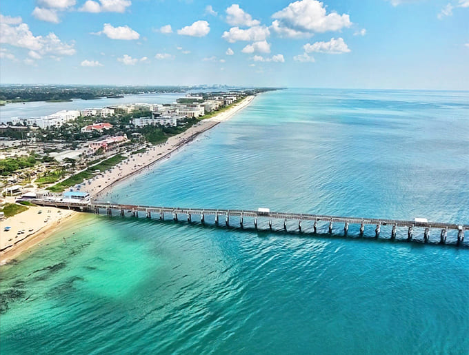 Aerial paradise: Where turquoise meets civilization at Lake Worth Beach, with that iconic pier stretching like a wooden welcome mat into the Atlantic.