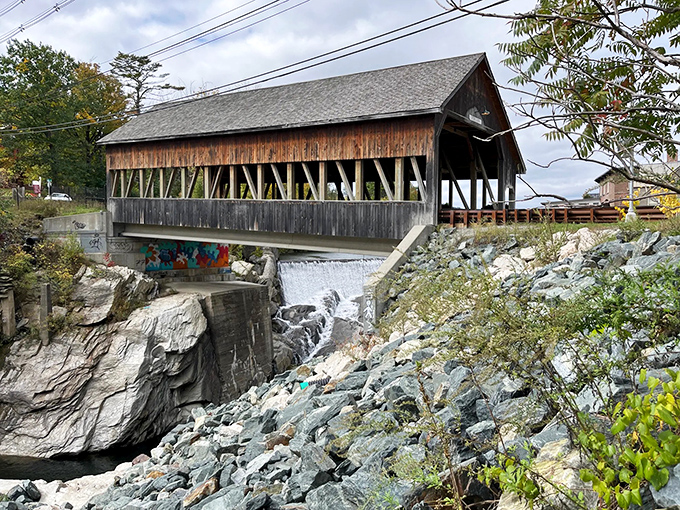 A charming covered bridge spans rushing water, blending historic craftsmanship with the beauty of the surrounding landscape.
