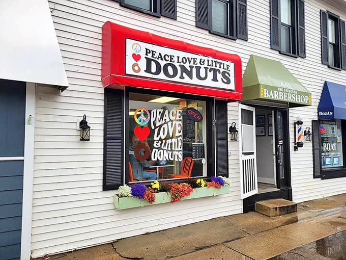 The vibrant red storefront of Peace, Love & Little Donuts beckons passersby with its groovy signage and flower-box charm.