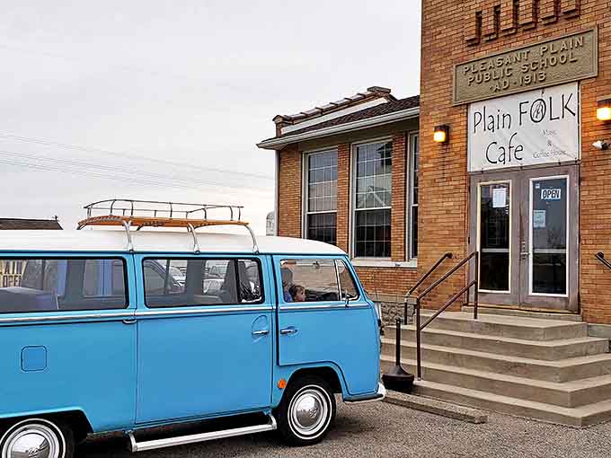 A vintage blue VW bus greets visitors outside the historic 1913 Pleasant Plain schoolhouse, promising groovy vibes and comfort food inside.