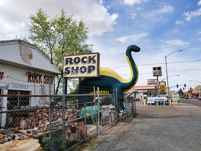 The iconic dinosaur sentinel guards Rainbow Rock Shop like a prehistoric bouncer checking IDs at Earth's geological nightclub.