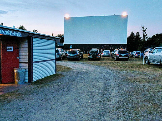 The classic snack bar and towering white screen await as dusk settles over Sunset Drive-In, promising an evening of cinematic magic.