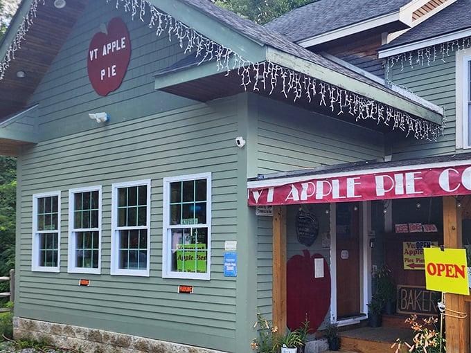 The charming green exterior of Vermont Apple Pie Bakery beckons hungry travelers with its iconic red signage and promise of homemade delights inside.