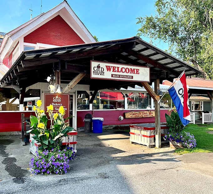 The iconic red exterior of Cold Hollow Cider Mill welcomes visitors with rustic charm and vibrant flower displays &ndash; Vermont's equivalent of a culinary red carpet.