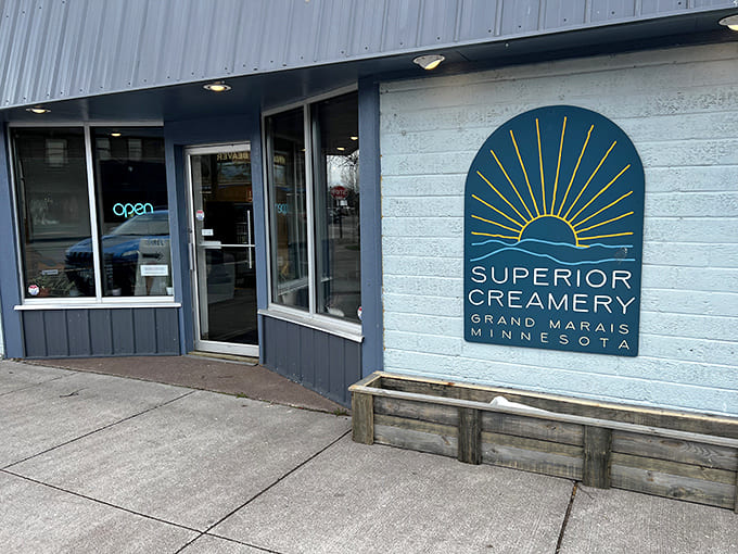 The blue and white exterior of Superior Creamery beckons like a lighthouse for hungry travelers, promising treasures beyond just frozen treats along Grand Marais's charming streets.