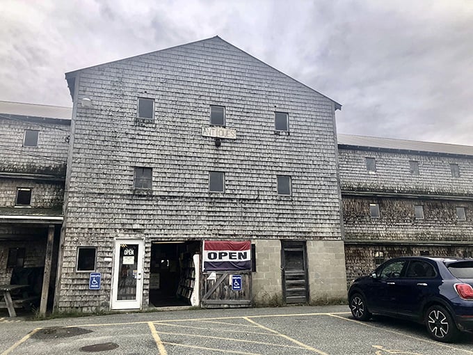 The weathered exterior of Big Chicken Barn Books & Antiques stands as a rustic time capsule against Maine's changeable skies.