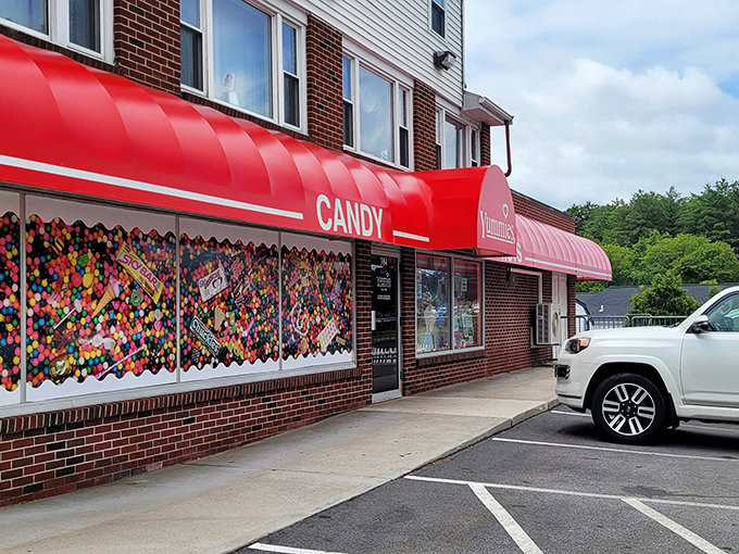 The iconic red awning of Yummies Candy and Nuts stands out like a beacon of sweetness, promising childhood nostalgia inside.