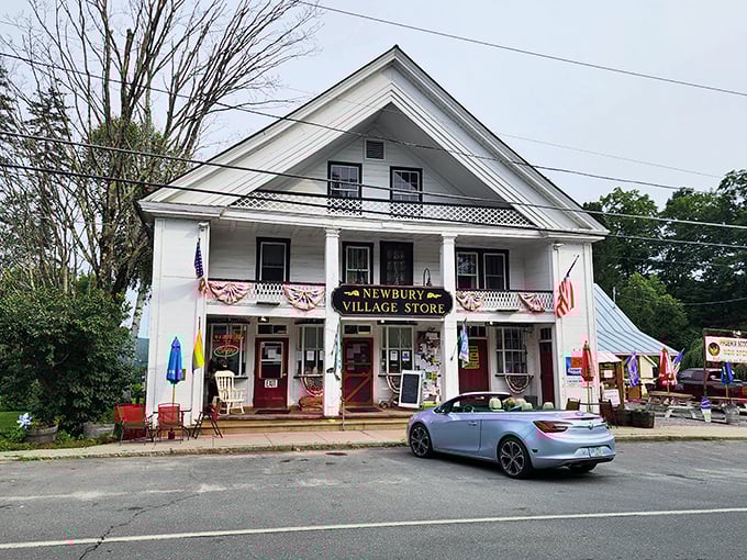 The classic white clapboard exterior of Newbury Village Store stands proudly along Vermont's roadside, American flags fluttering in welcome.