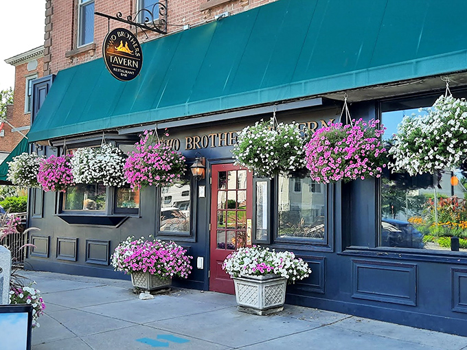 The inviting facade of Two Brothers Tavern, with its signature teal awning and cascading flower baskets, stands as Montpelier's culinary beacon.