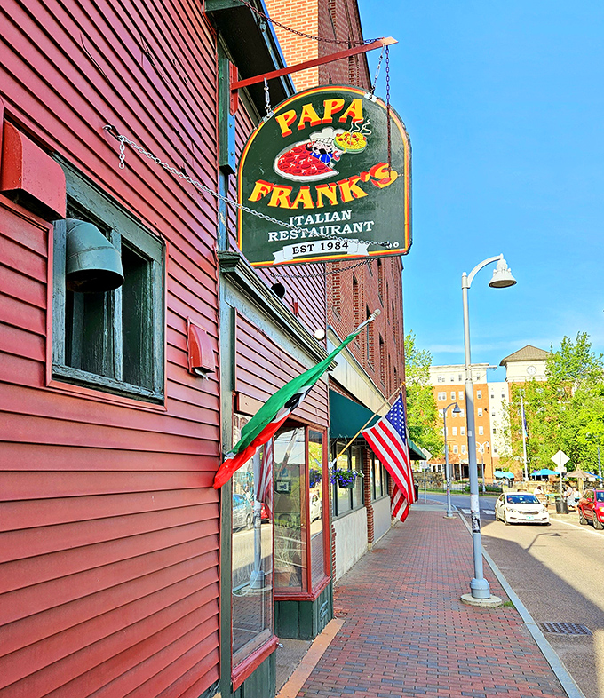 The iconic red exterior of Papa Frank's stands like a beacon of Italian comfort food in Barre, Vermont, complete with its welcoming sign and flags.