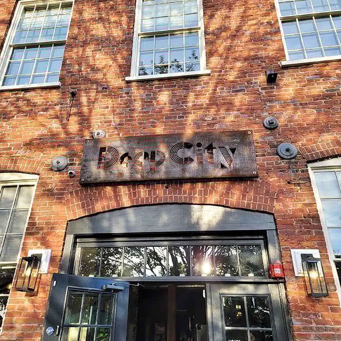 Deep City's weathered metal sign against warm brick promises culinary adventures within &ndash; industrial chic meets Vermont charm.