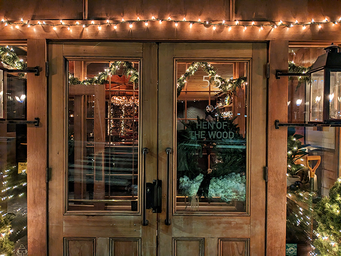 Wooden doors adorned with twinkling lights welcome you to Hen of the Wood, where Vermont's culinary magic awaits behind this unassuming entrance.