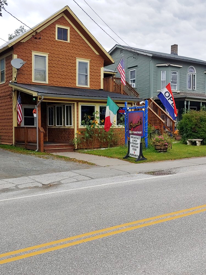 Bernie's exterior welcomes hungry travelers with its charming orange-shingled facade and colorful flags &ndash; Vermont's most delicious surprise hiding in plain sight.