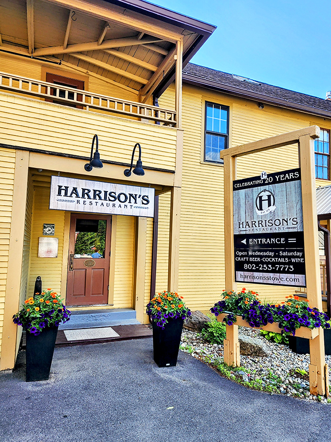 The welcoming yellow exterior of Harrison's Restaurant beckons hungry travelers with colorful flower boxes and a promise of Vermont hospitality inside.