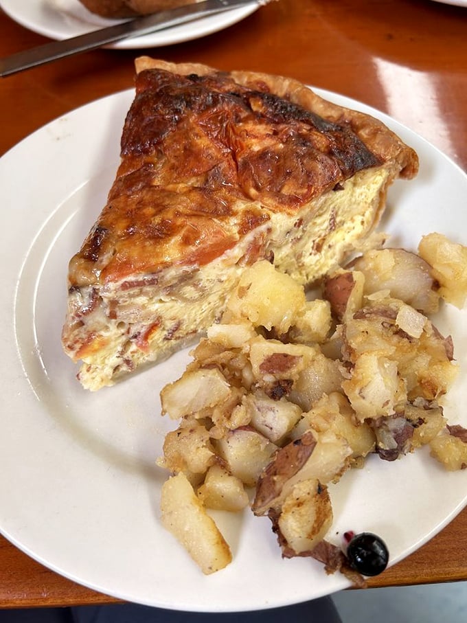 Quiche that defies gravity with its impossibly light custard, surrounded by home fries that have achieved the perfect crisp-to-tender ratio.