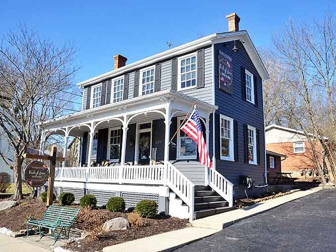 This historic blue home turned business welcomes visitors with classic American charm &ndash; white porch railings and patriotic flags included.