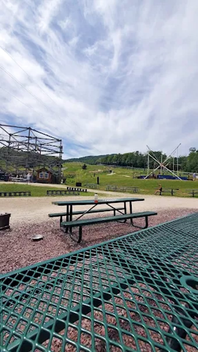 Picnic tables offer perfect viewing spots for spectators to watch loved ones navigate the towering structure above.