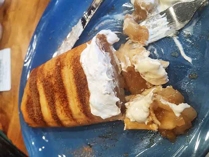A warm apple crepe arrives for dessert, its cinnamon-spiced filling peeking out from beneath a cloud of whipped cream &ndash; sweet satisfaction after a hearty meal.