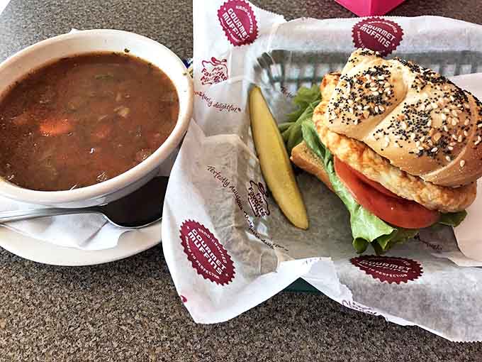 A perfect pairing: hearty soup alongside a chicken sandwich on a sesame bagel, complete with the signature pickle spear.