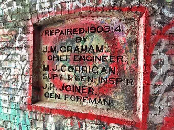 This weathered plaque reveals the tunnel's 1906 repair history, a tangible connection to its railroad heyday.