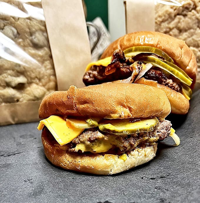 Fresh beef sliders lined up like soldiers, ready for battle against hunger with their caramelized onion ammunition and cheese armor.