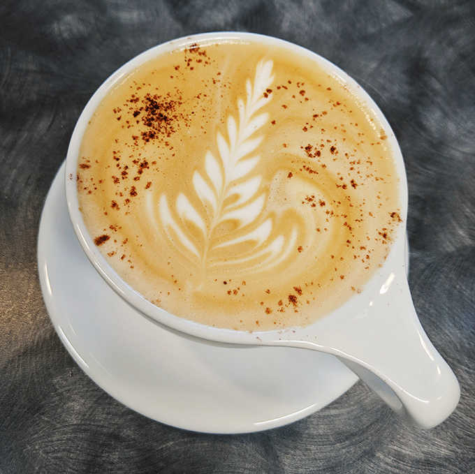 Each latte is a canvas for barista artistry, where the delicate leaf pattern isn't just decoration but evidence of the care behind every cup.