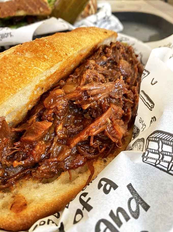 Pulled pork elevated beyond backyard barbecue status &ndash; tender, saucy, and nestled in bread that somehow contains the delicious chaos without surrendering to it.