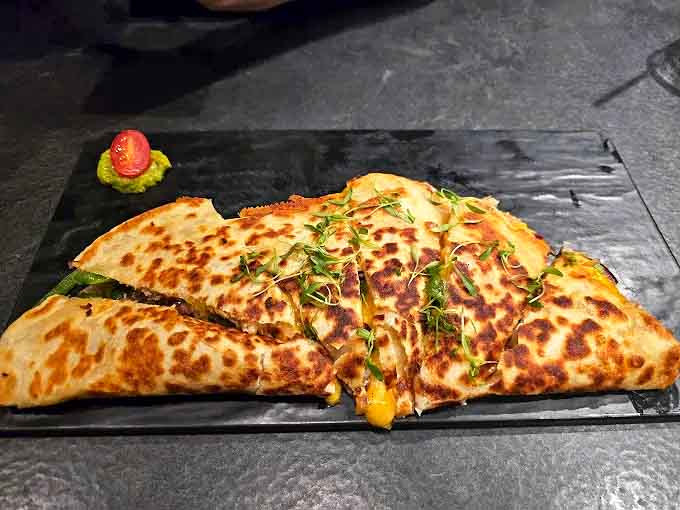This quesadilla isn't just folded &ndash; it's transformed into a golden-brown envelope delivering cheesy, herb-flecked messages straight to your soul.