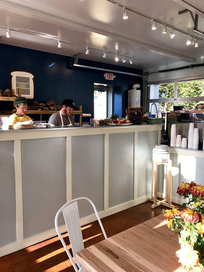 The clean, modern interior with exposed ductwork and warm lighting creates the perfect backdrop for serious baking with a friendly, approachable vibe throughout.