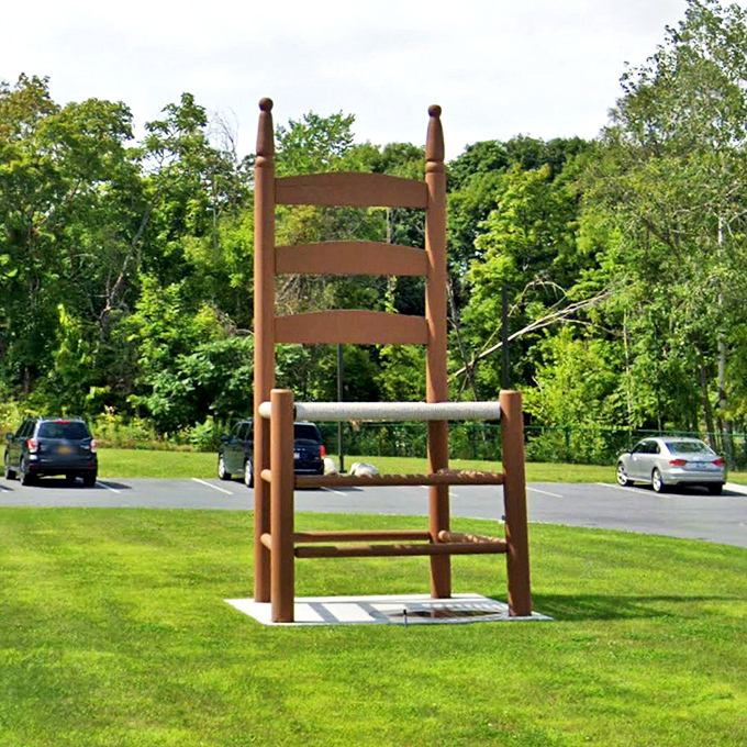 Set against lush summer greenery, the chair creates a striking silhouette. Vermont's natural beauty provides the perfect backdrop for this wooden behemoth's quiet majesty.