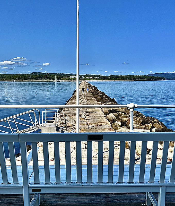 A peaceful bench awaits tired travelers, offering a moment to rest and absorb the breathtaking maritime panorama stretching to the horizon.