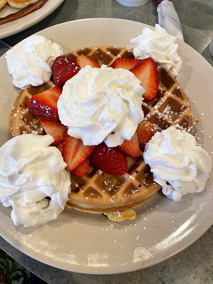 A waffle that thinks it's dessert. Crispy, golden, and topped with fresh strawberries and clouds of whipped cream &ndash; breakfast bliss!
