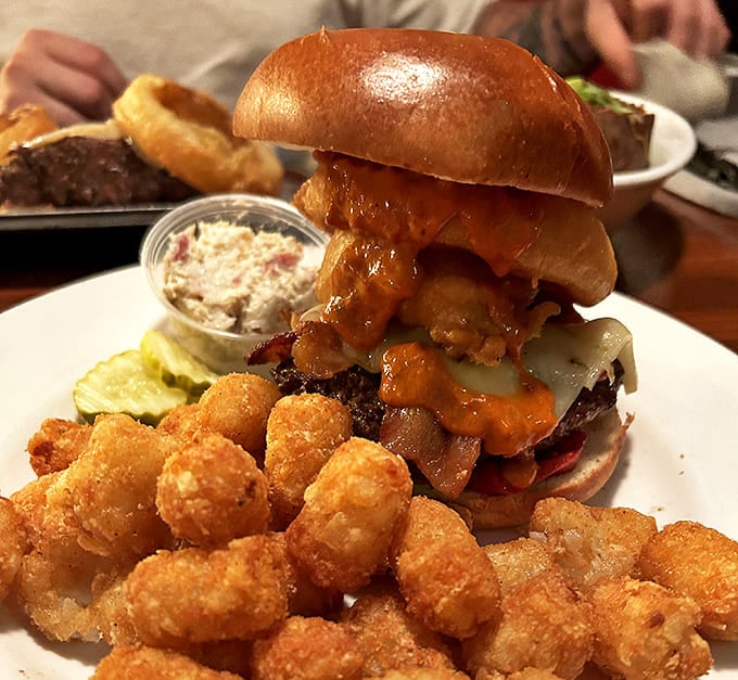 The Whiskey BBQ Burger towers with onion rings and tater tots, a glorious monument to everything right about American tavern food.