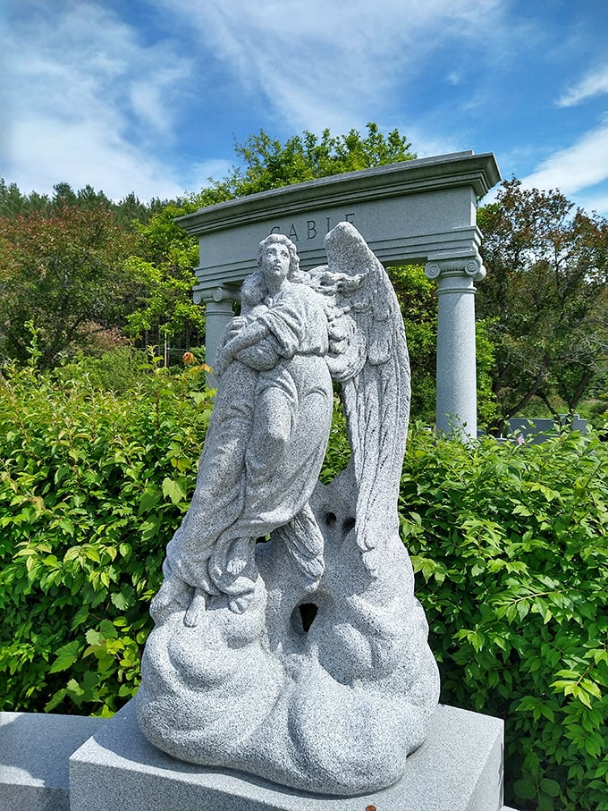 Graceful angel sculpture rises among vibrant greenery at Hope Cemetery, offering a peaceful, comforting presence beneath Vermont&rsquo;s bright summer sky.