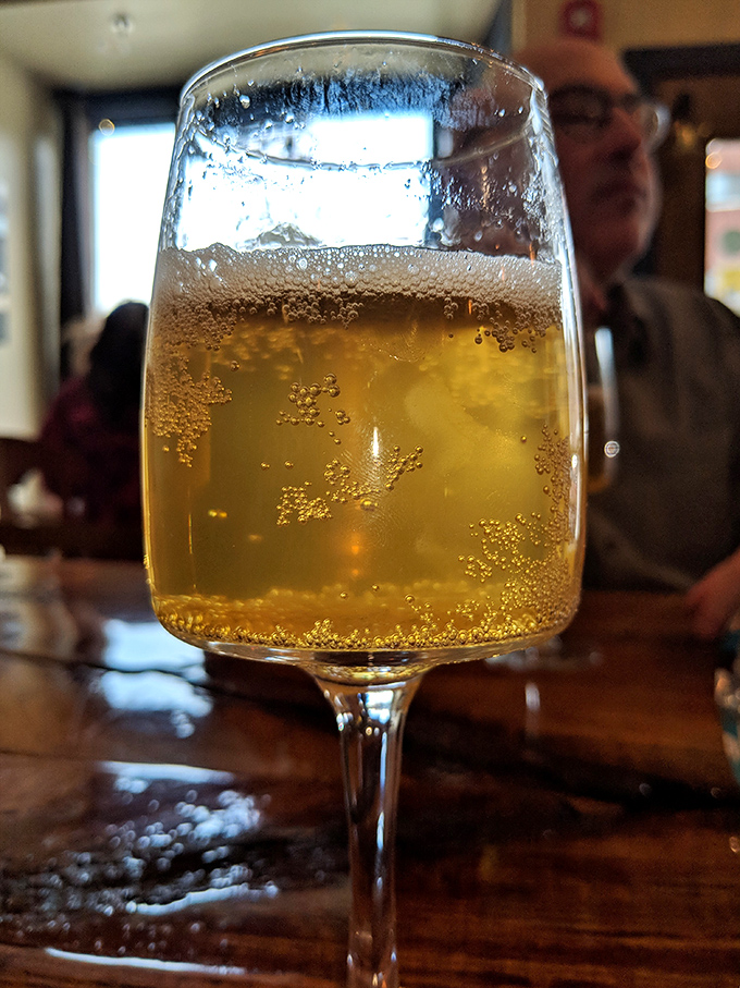 Golden bubbles rise in a glass of local craft cider, the perfect companion to cut through the richness of your sandwich.