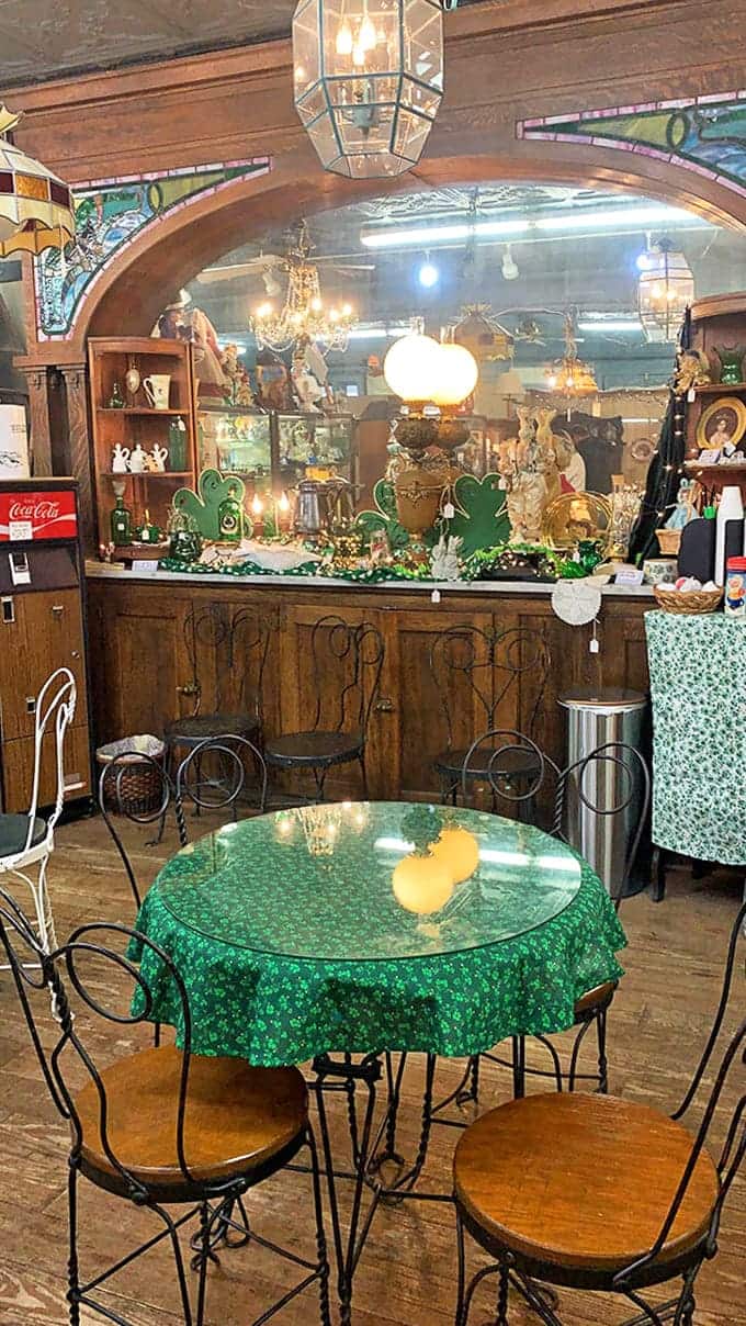 Blue wainscoting and warm wood create a homey backdrop for this dining vignette, where mismatched vintage chairs invite imaginary dinner conversations.