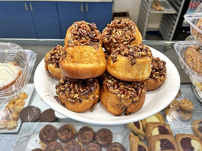 Sticky pecan rolls stacked high like edible jewelry, their caramelized tops glistening with promise of the sweet, nutty experience to come.