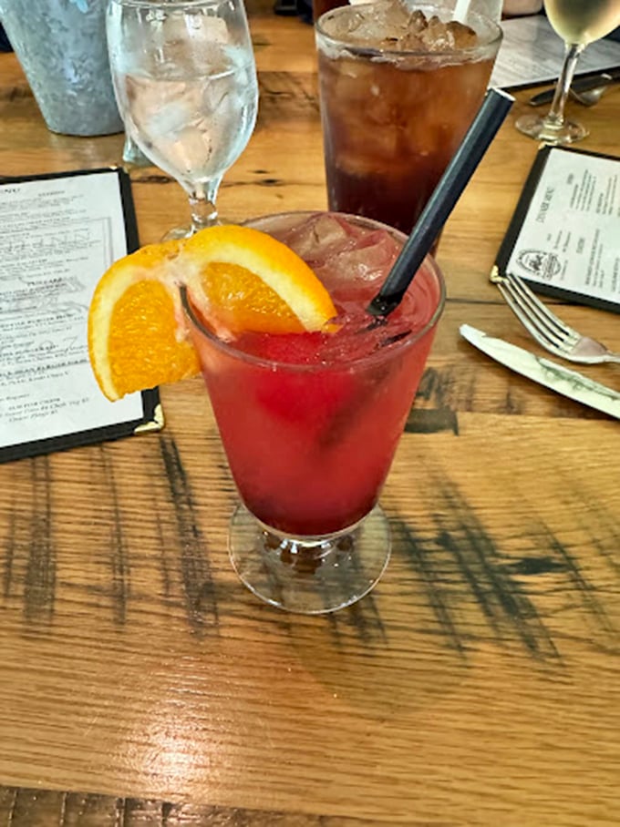 This crimson cocktail, garnished with fresh orange, brings a splash of sophisticated fun to the traditional pub setting.