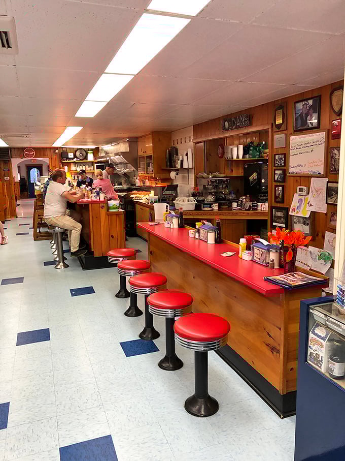 The counter where breakfast dreams come true, red-topped and ready for regulars who've been claiming the same seats for decades.