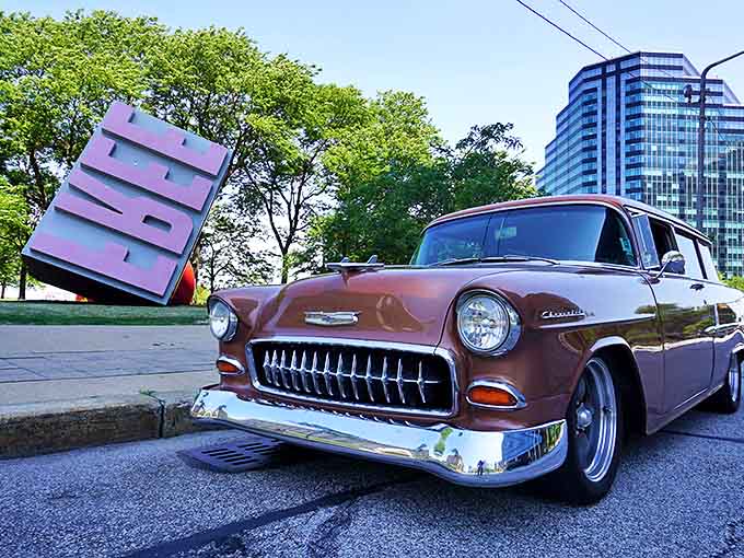 A vintage car poses alongside the Free Stamp, two different eras of American design having an unexpected conversation across time.