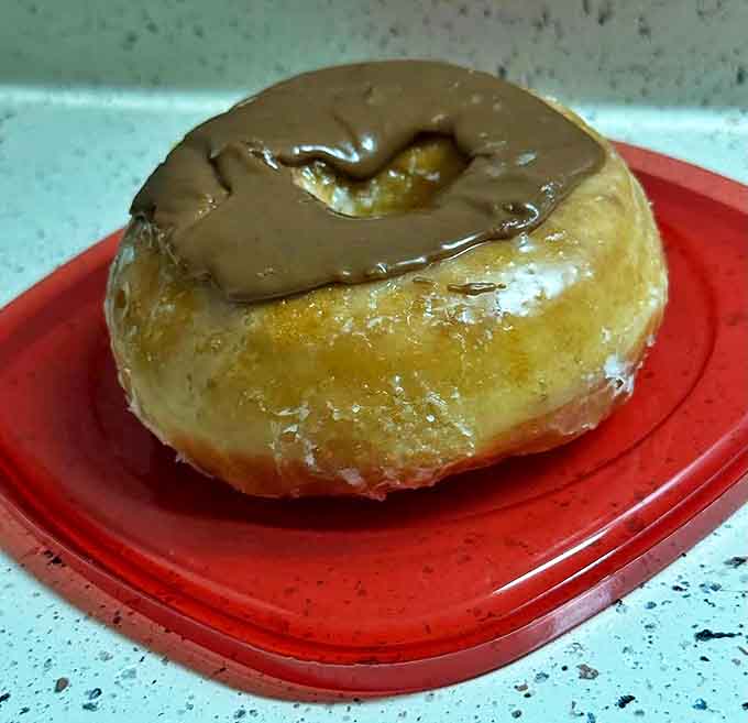 A perfectly executed glazed donut with chocolate topping demonstrates why simplicity, when done right, can be the ultimate luxury.