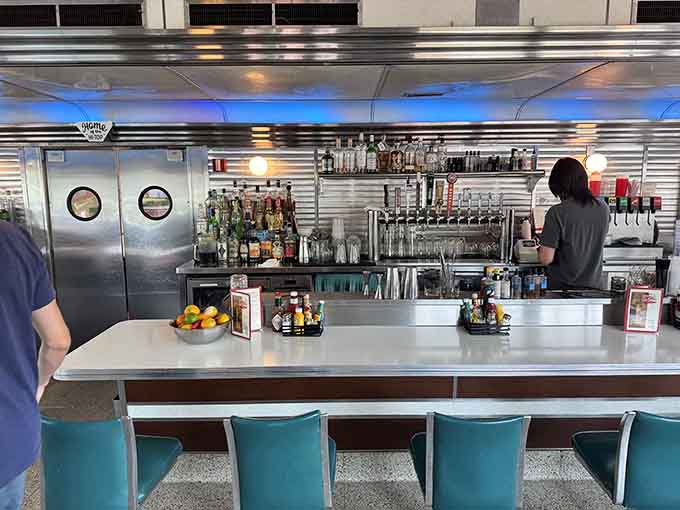 The counter stretches before you with swivel stools and a full bar setup, offering front-row seats to the breakfast theater happening in the kitchen.