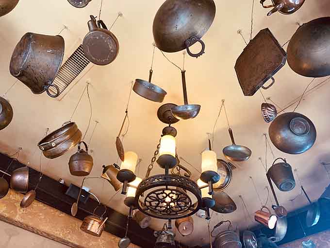 Eclectic ceiling display of antique pots and pans creates unexpected art from everyday kitchen tools.