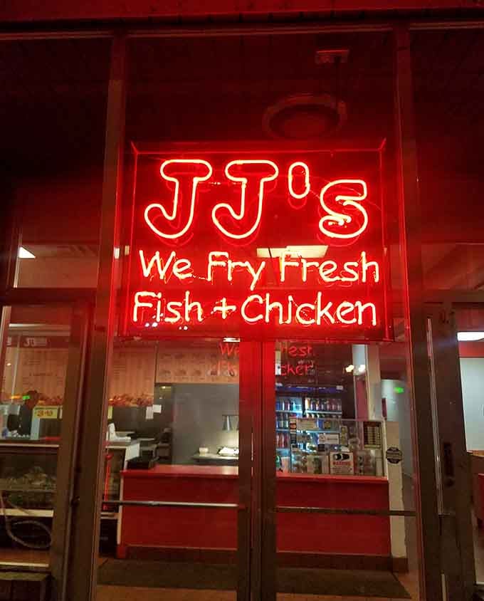 That neon sign glowing "We Fry Fresh Fish + Chicken" serves as both advertisement and solemn promise to hungry passersby.