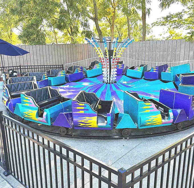 Sleek blue and purple cars await their next passengers, ready to spin riders into fits of dizzying delight.