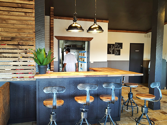 Industrial-style stools at the counter offer front-row seats to the kitchen action, perfect for solo diners or those who appreciate culinary craftsmanship up close.