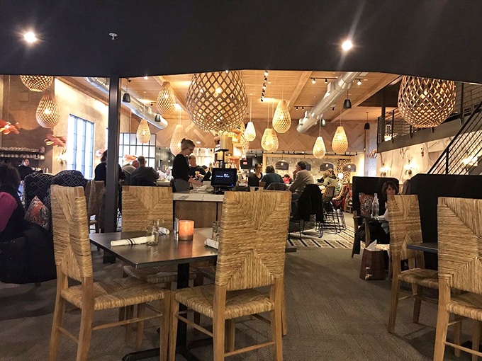 The dining room buzzes with energy as patrons enjoy the warm ambiance created by natural materials and thoughtful lighting design.
